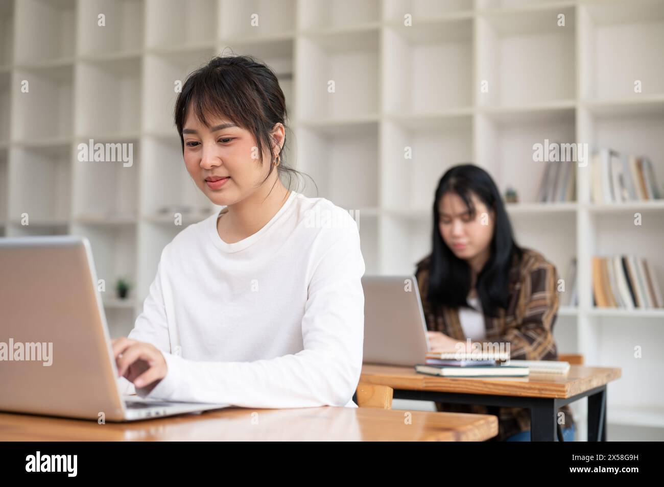 A positive, charming young Asian female university student is using her ...