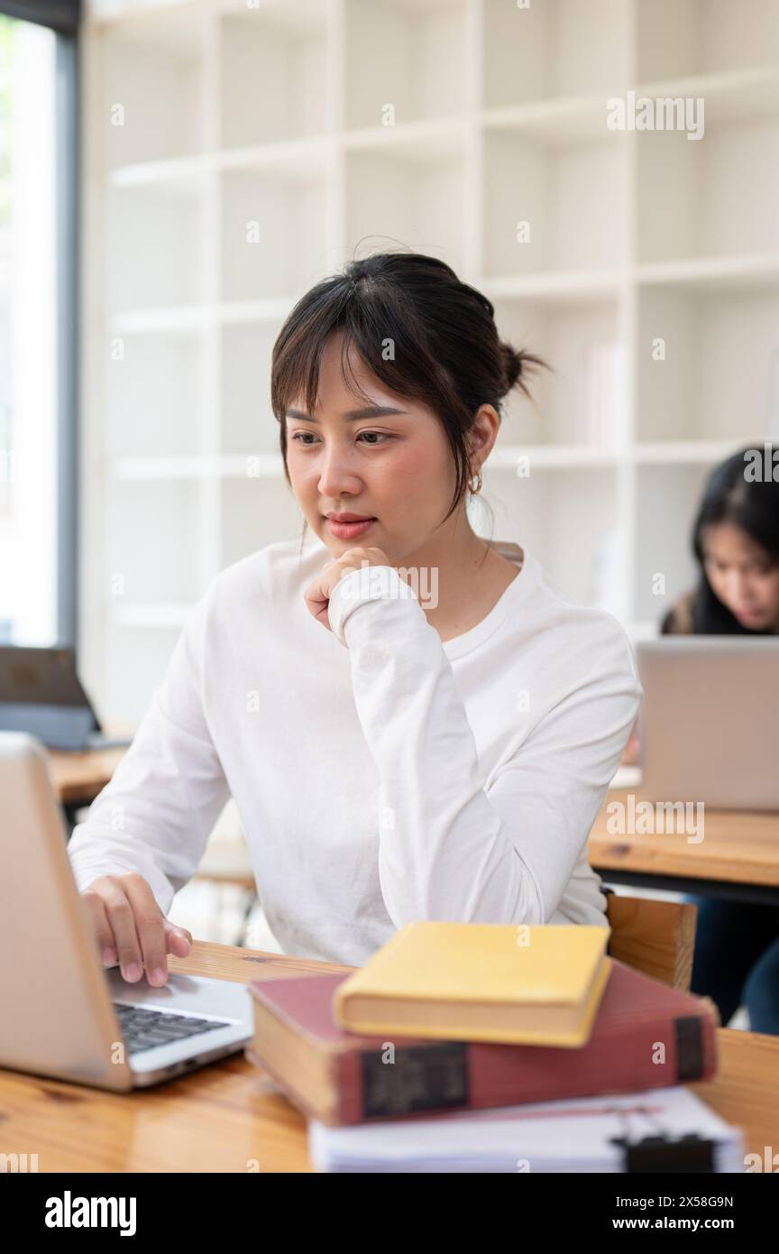 A beautiful young Asian female student focusing on her work on her ...