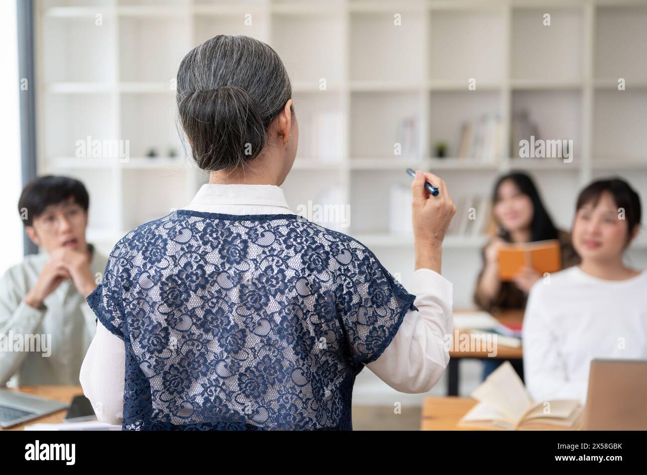 A back view image of a mature Asian female teacher professor giving a ...