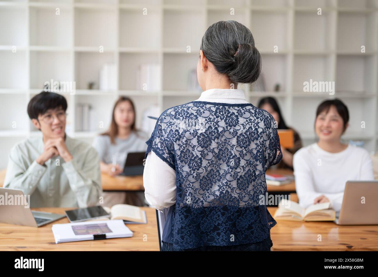 A back view image of a mature Asian female teacher professor giving a ...