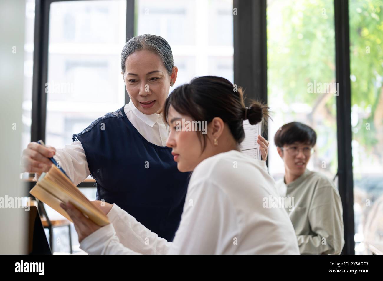 Senior Asian female teacher professor helping and explaining difficult ...