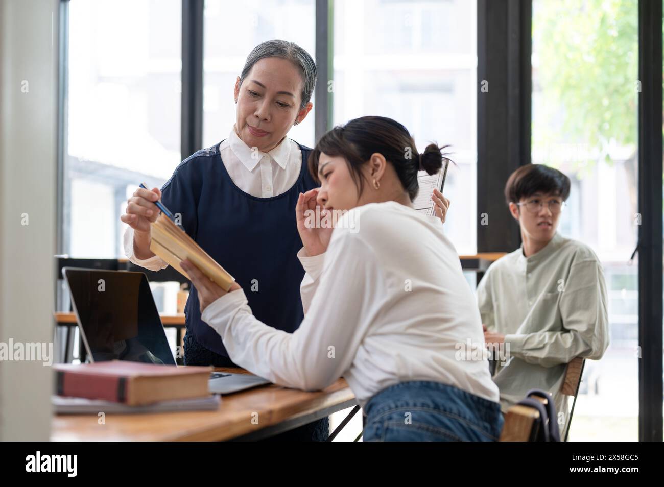 Senior Asian female teacher professor helping and explaining difficult ...