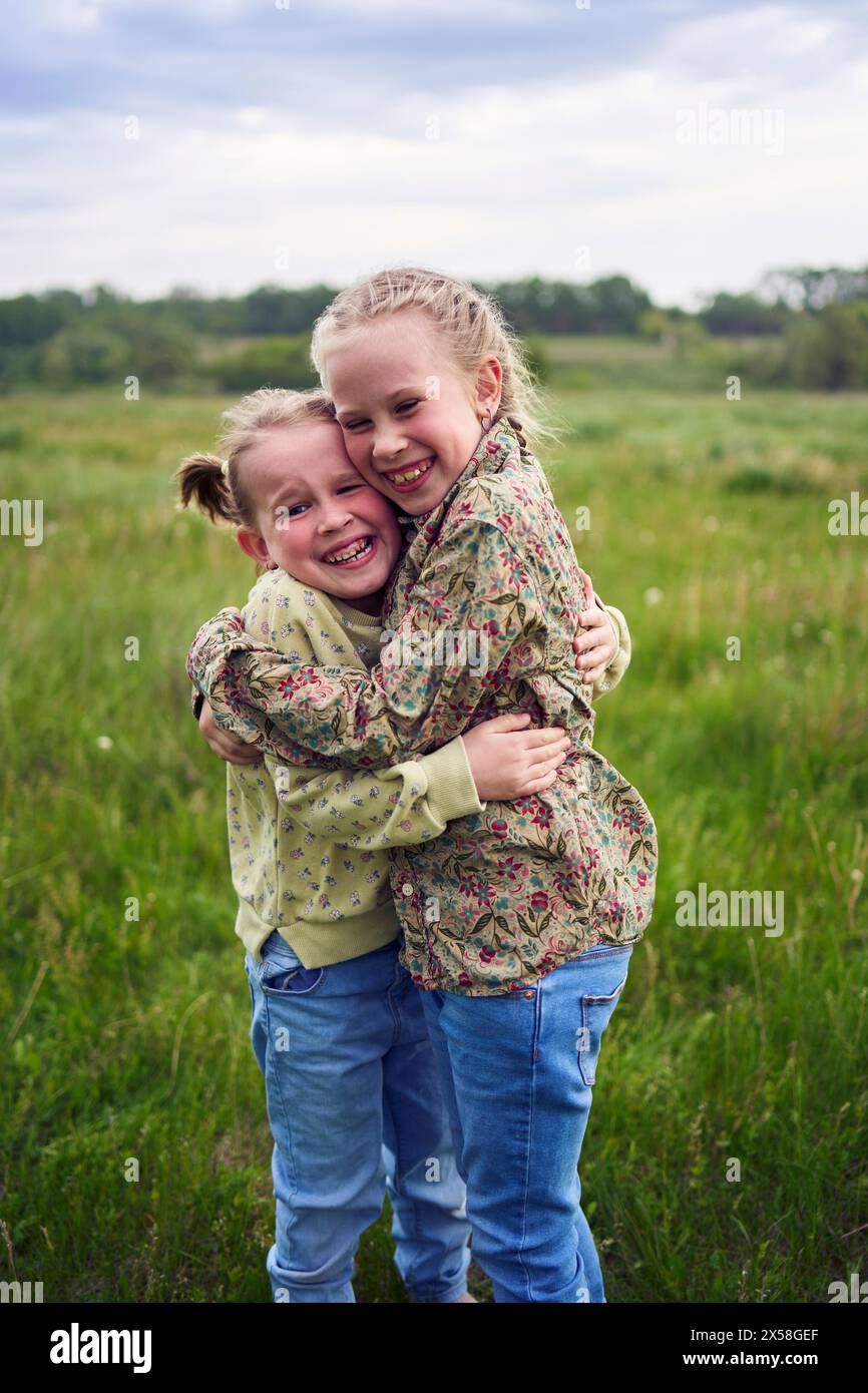 sisters hug and protect each other from the wind in the field Stock ...
