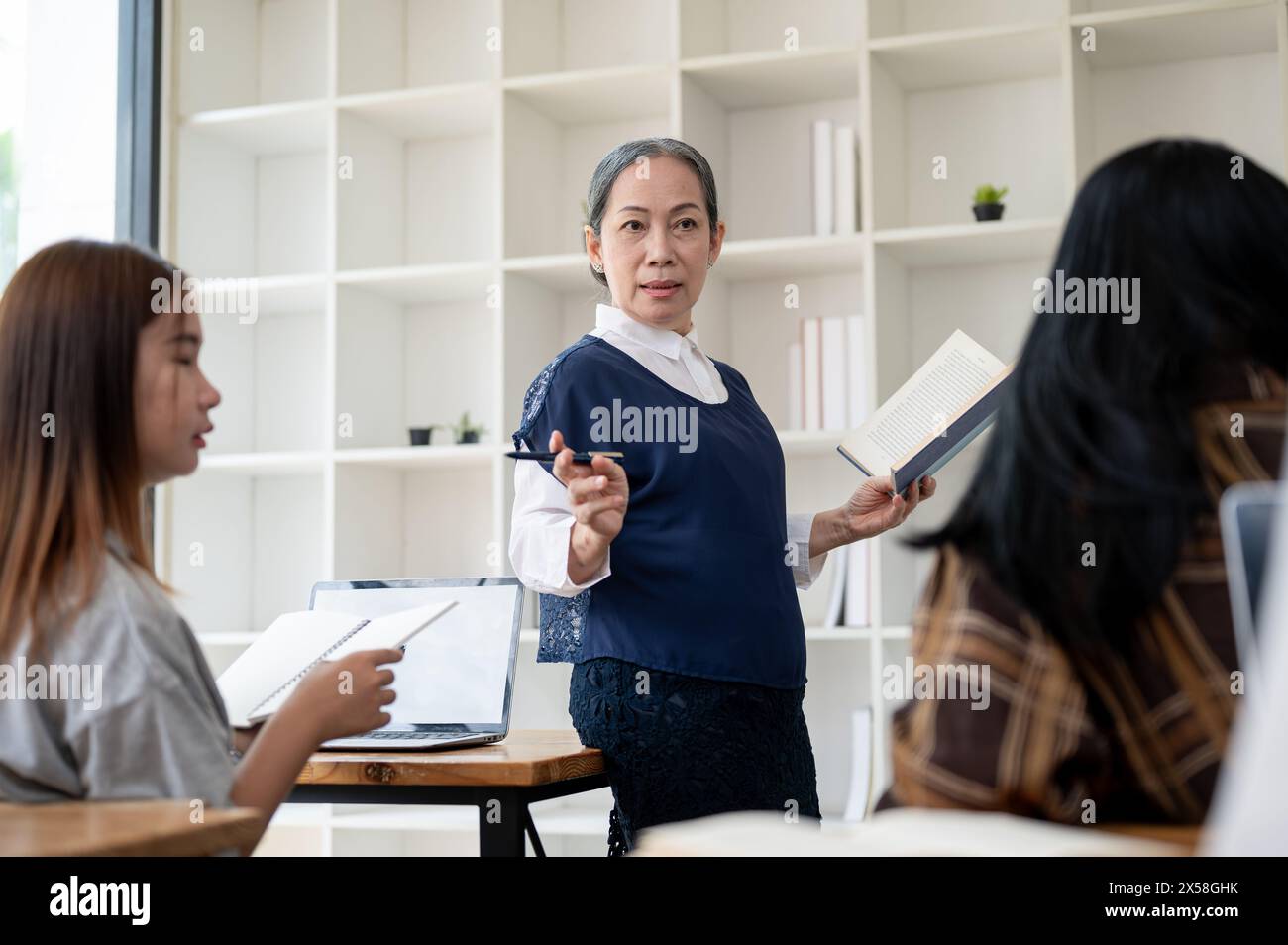 A professional mature Asian female teacher or professor teaching in the ...