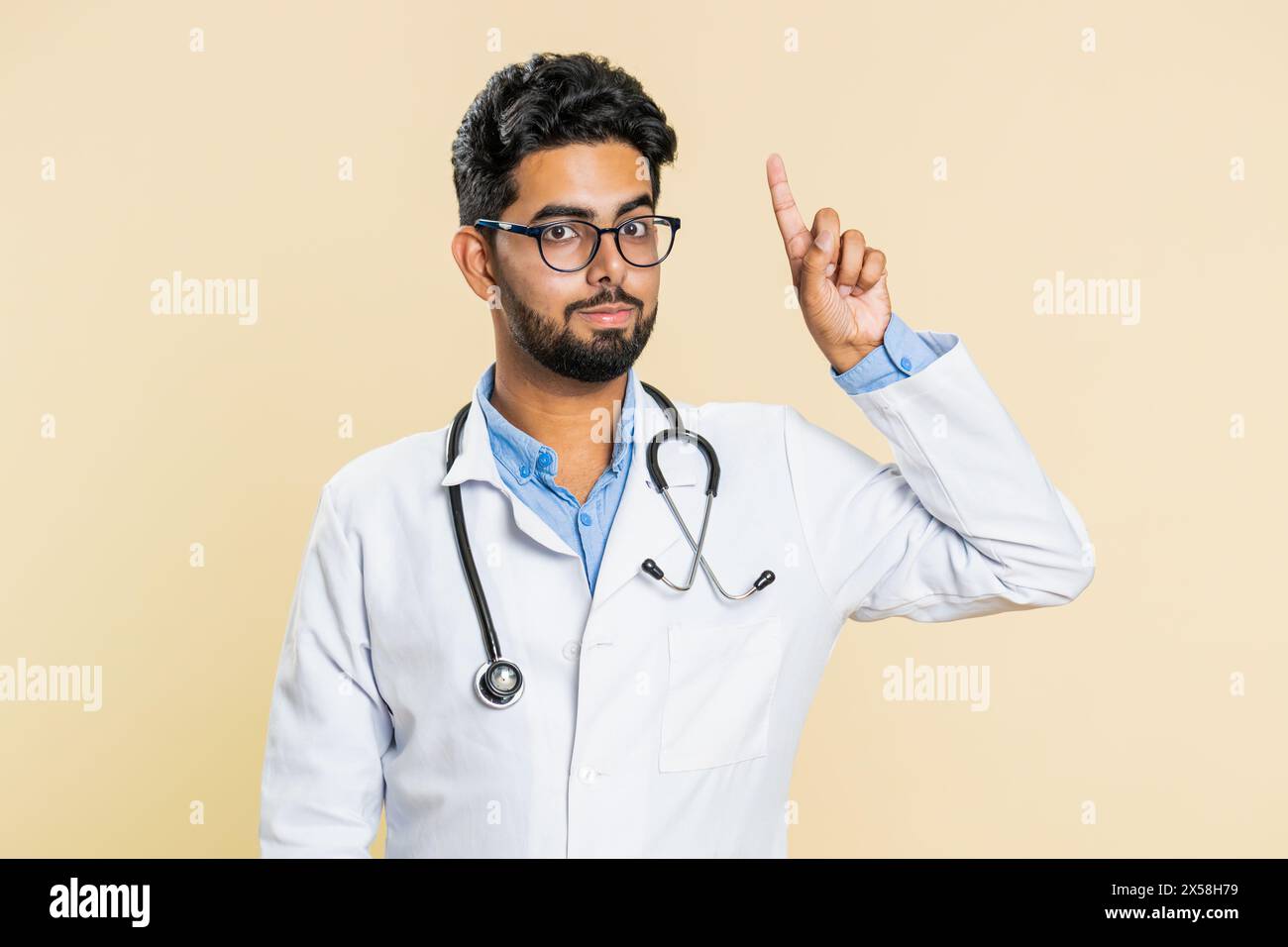 Eureka. Inspired Indian young doctor cardiologist man pointing finger ...