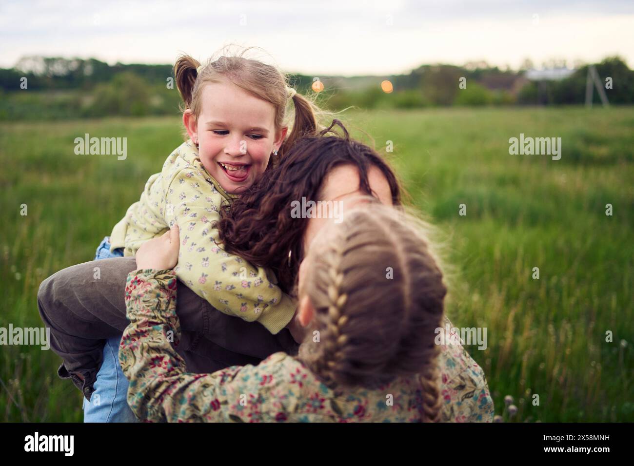 mother rolls her daughters on her back, playing horse, kisses and hugs ...