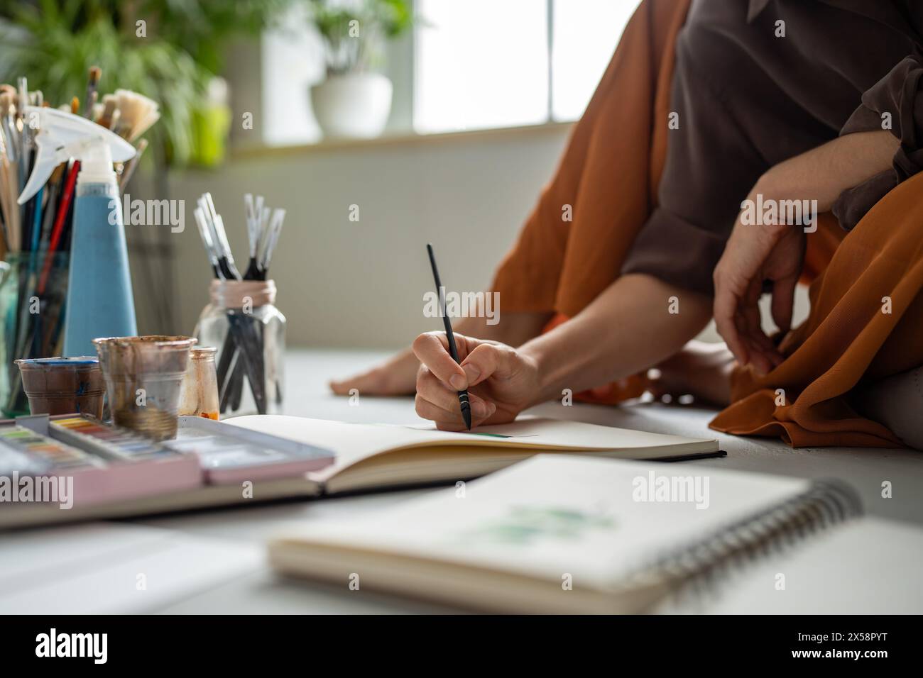 Focused female artist painting with brush. Woman drawing sketches using ...