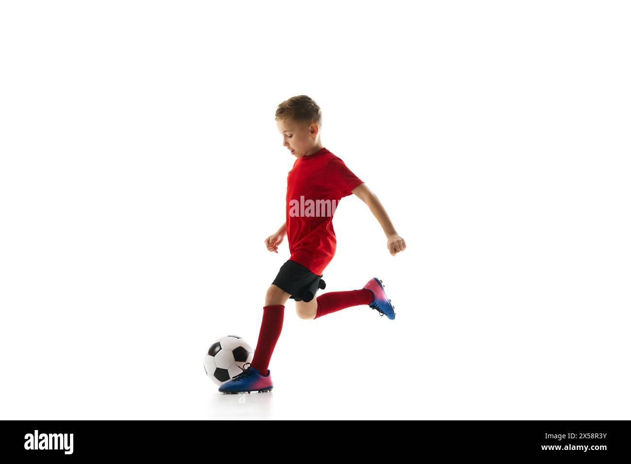 Little athlete boy, training dribbling ball and passing in motion ...