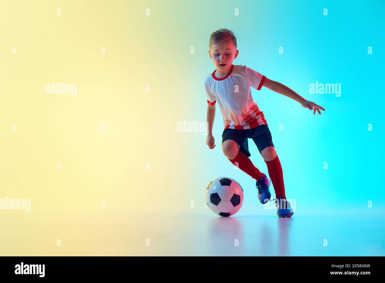 Sports photo of boy dressed in soccer kit, frozen in moment of action ...