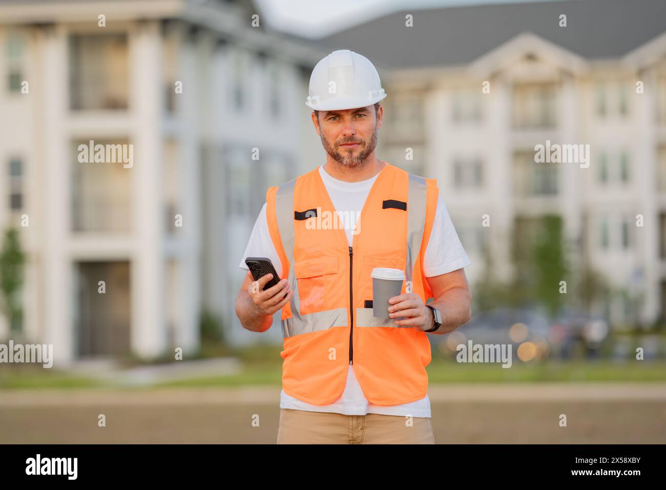 Engineer builder drinking take away coffee using phone on break ...