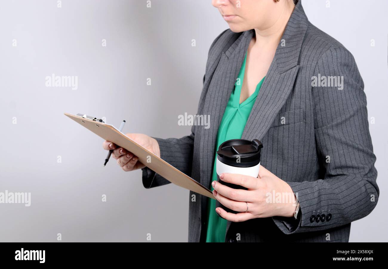 Close up of a business woman holding a clipboard and a cup of coffee ...