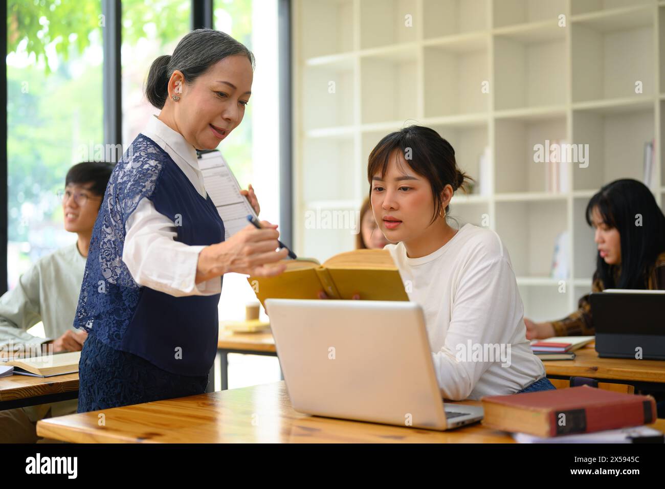 Senior lecturer helping student during lecture in the classroom Stock ...