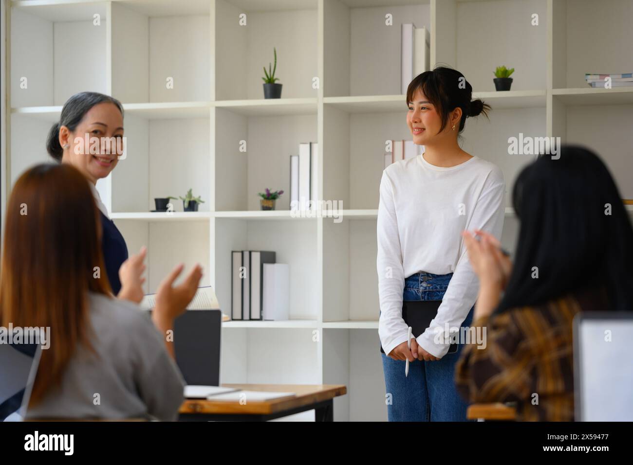 Smiling Asian student woman having presentation while her classmates ...