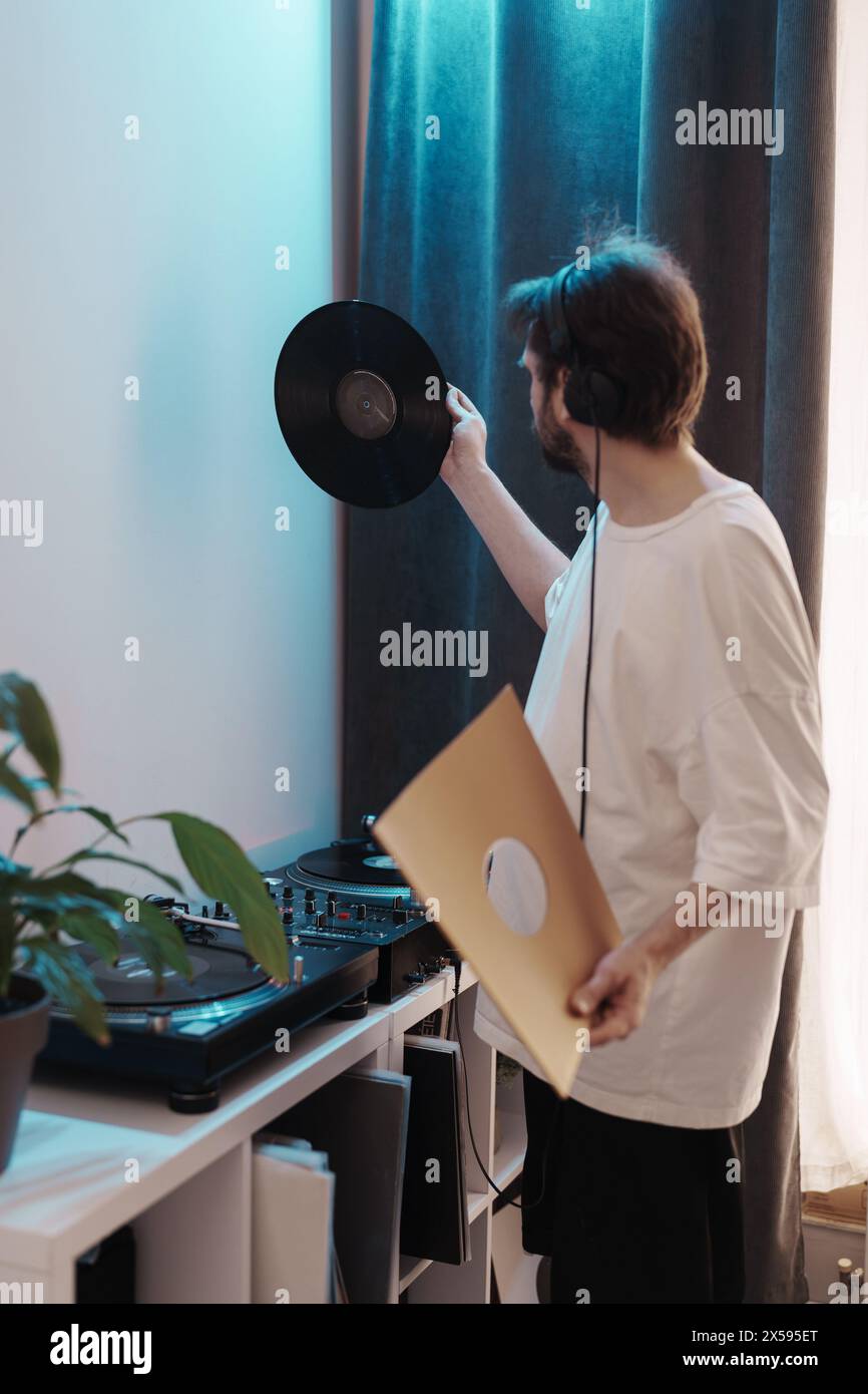 Man holding vinyl record next to turntable in cozy room Stock Photo - Alamy