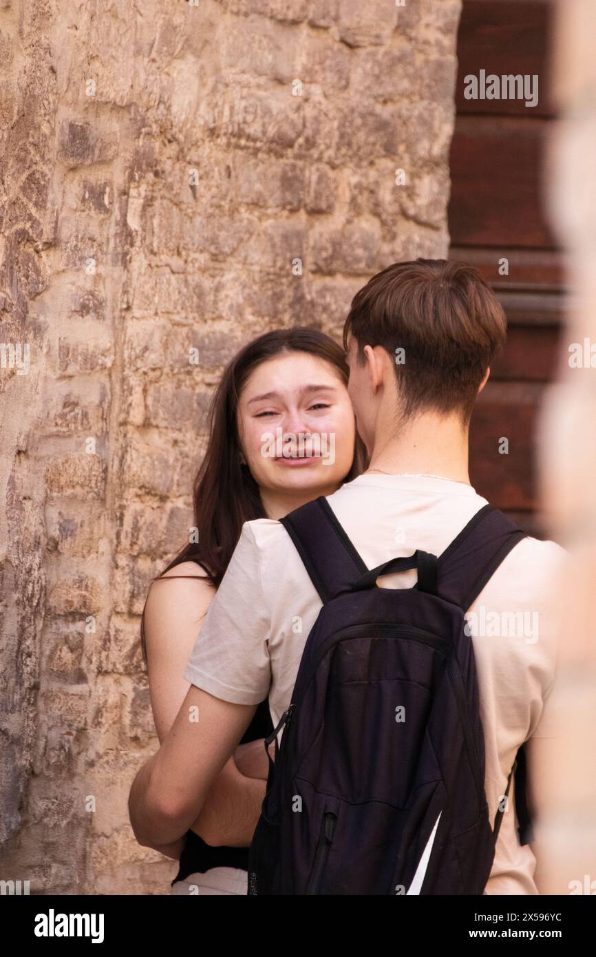 Urban landscape features crying woman comforted by supportive boyfriend ...