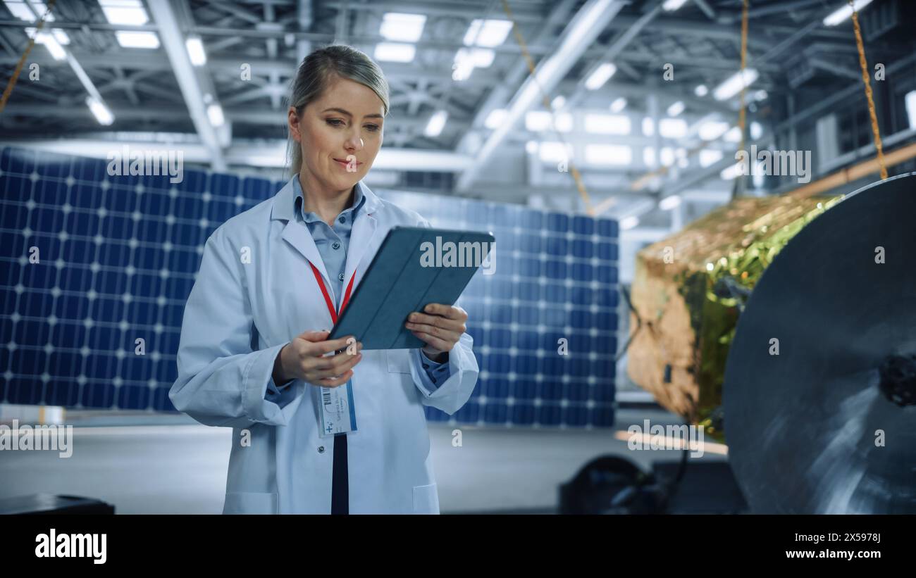 Female Engineer Uses Tablet Computer While Working On Satellite
