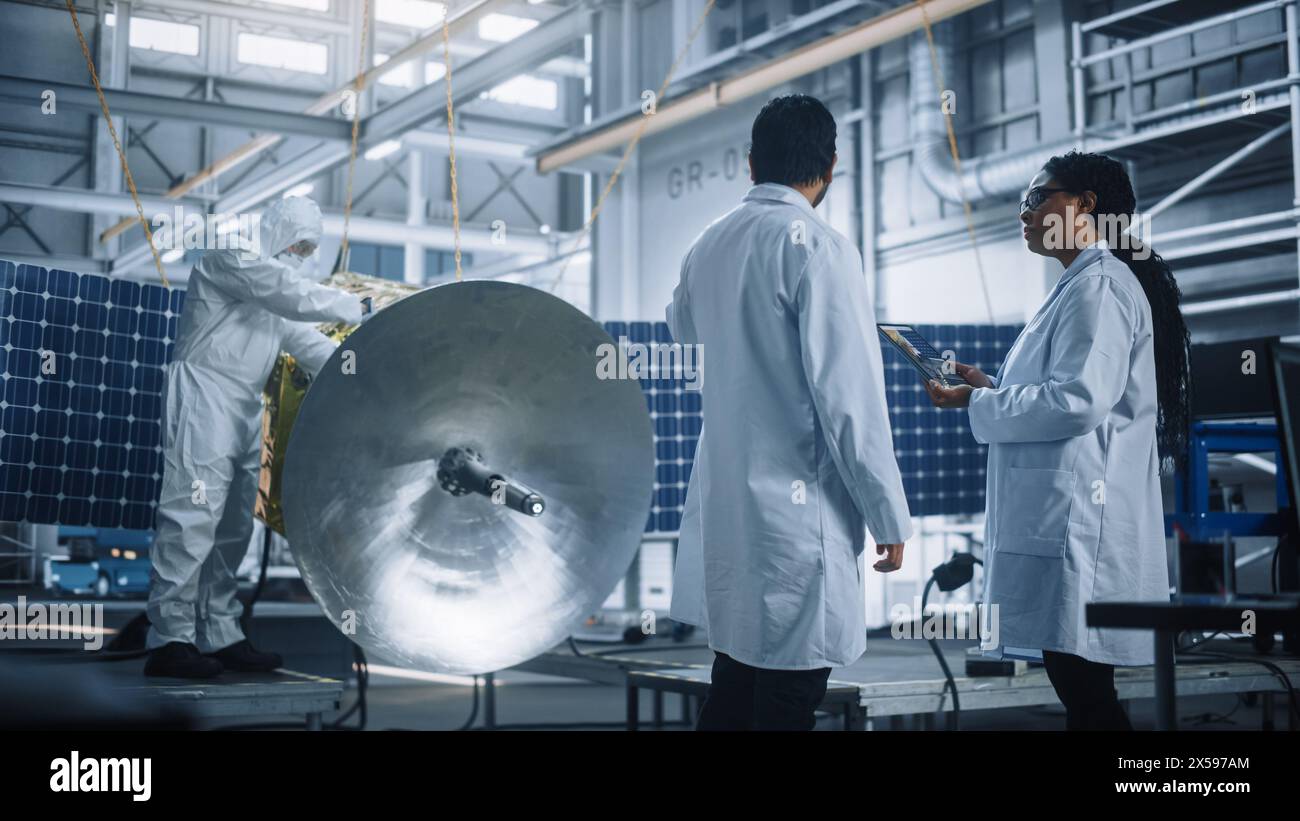Two Engineers Talk, Use Tablet Computer while Working on Satellite ...