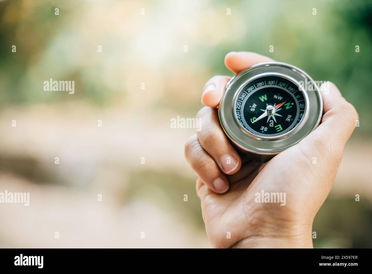 A traveler holding a compass in a park seeks guidance and direction in ...