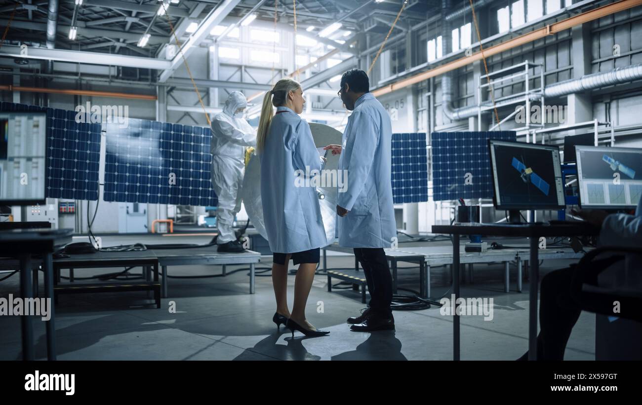 Two Engineers Talk, Use Tablet Computer while Working on Satellite ...