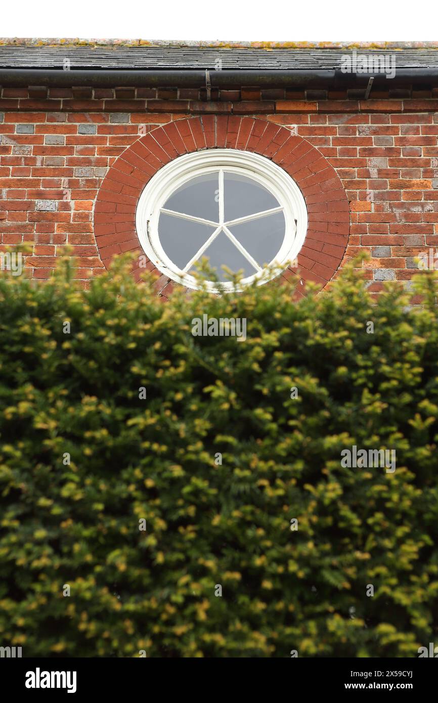 Round circular window in brick wall of house above a hedge Stock Photo ...