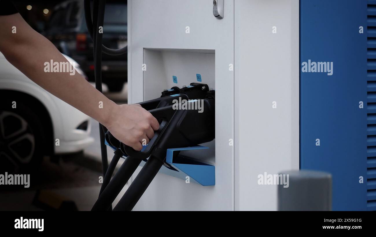 Driver of electric car hold batteries charger plug. Hand holding EV ...