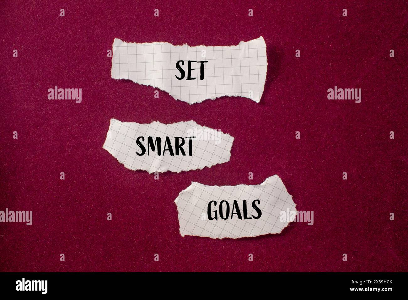 Set smart goals written on ripped white paper pieces with purple ...
