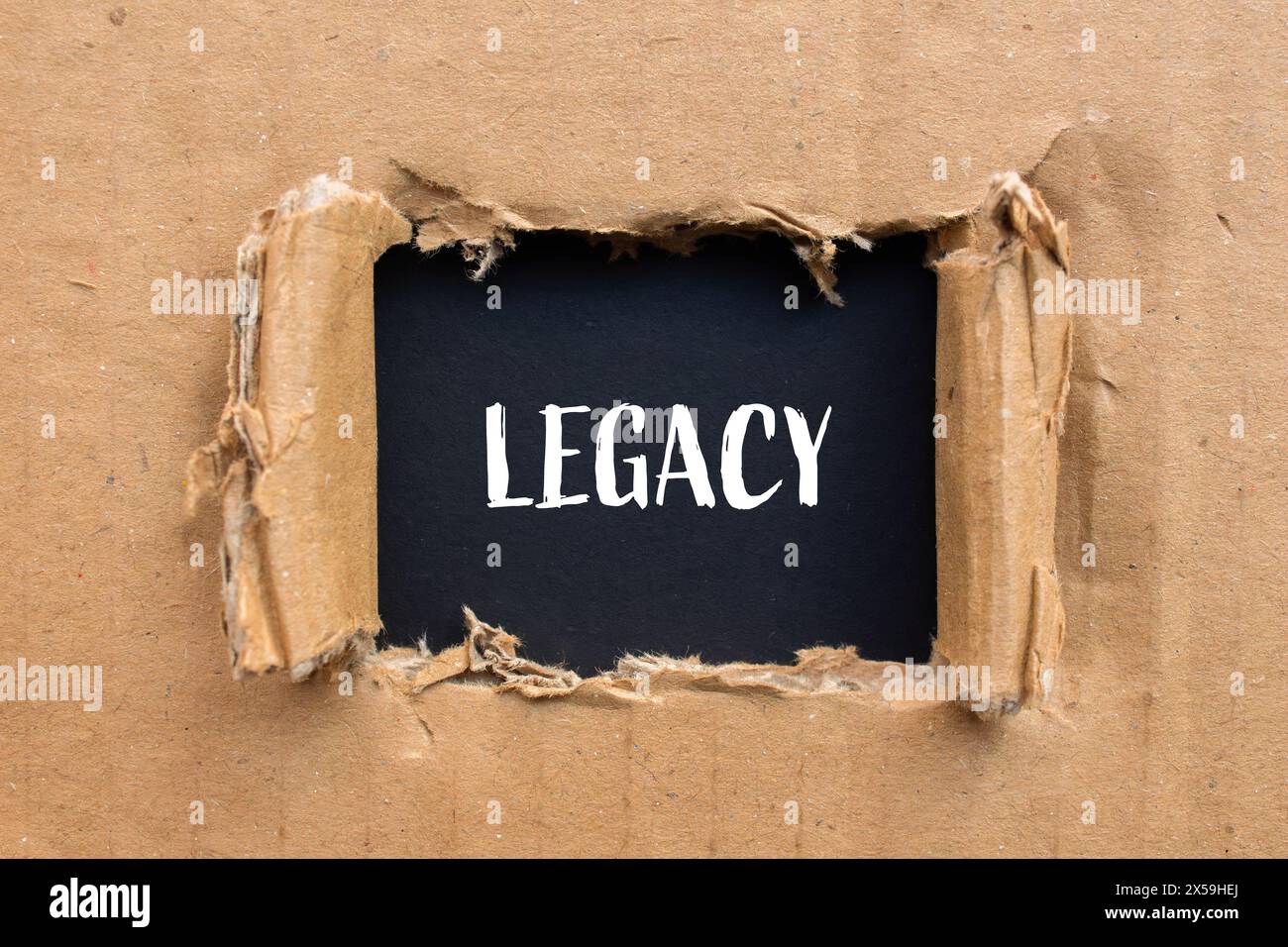 Legacy word written on ripped cardboard paper with black background ...
