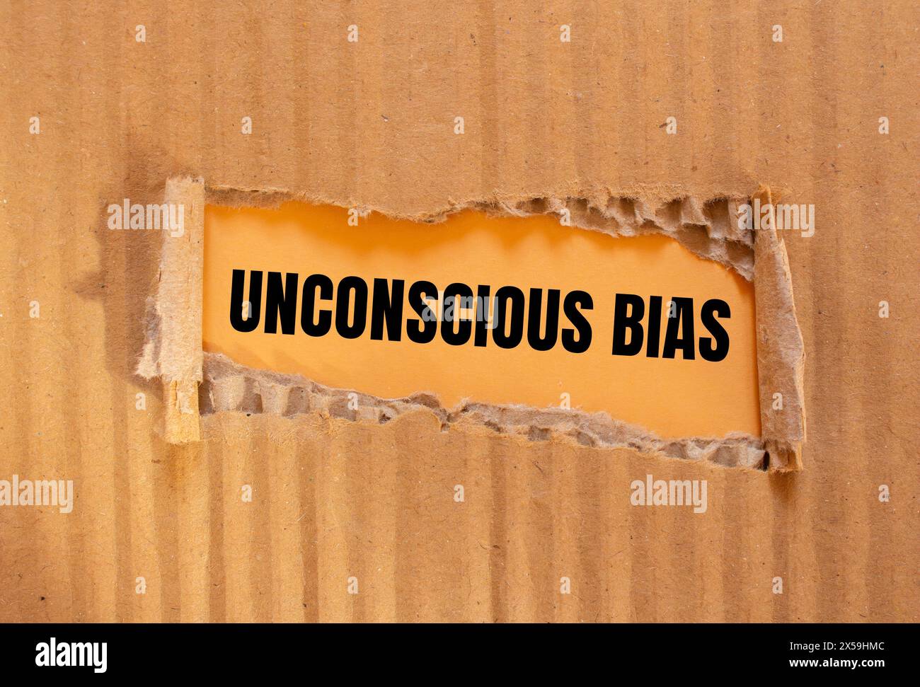 Unconscious bias words written on ripped cardboard paper with orange background. Conceptual ...