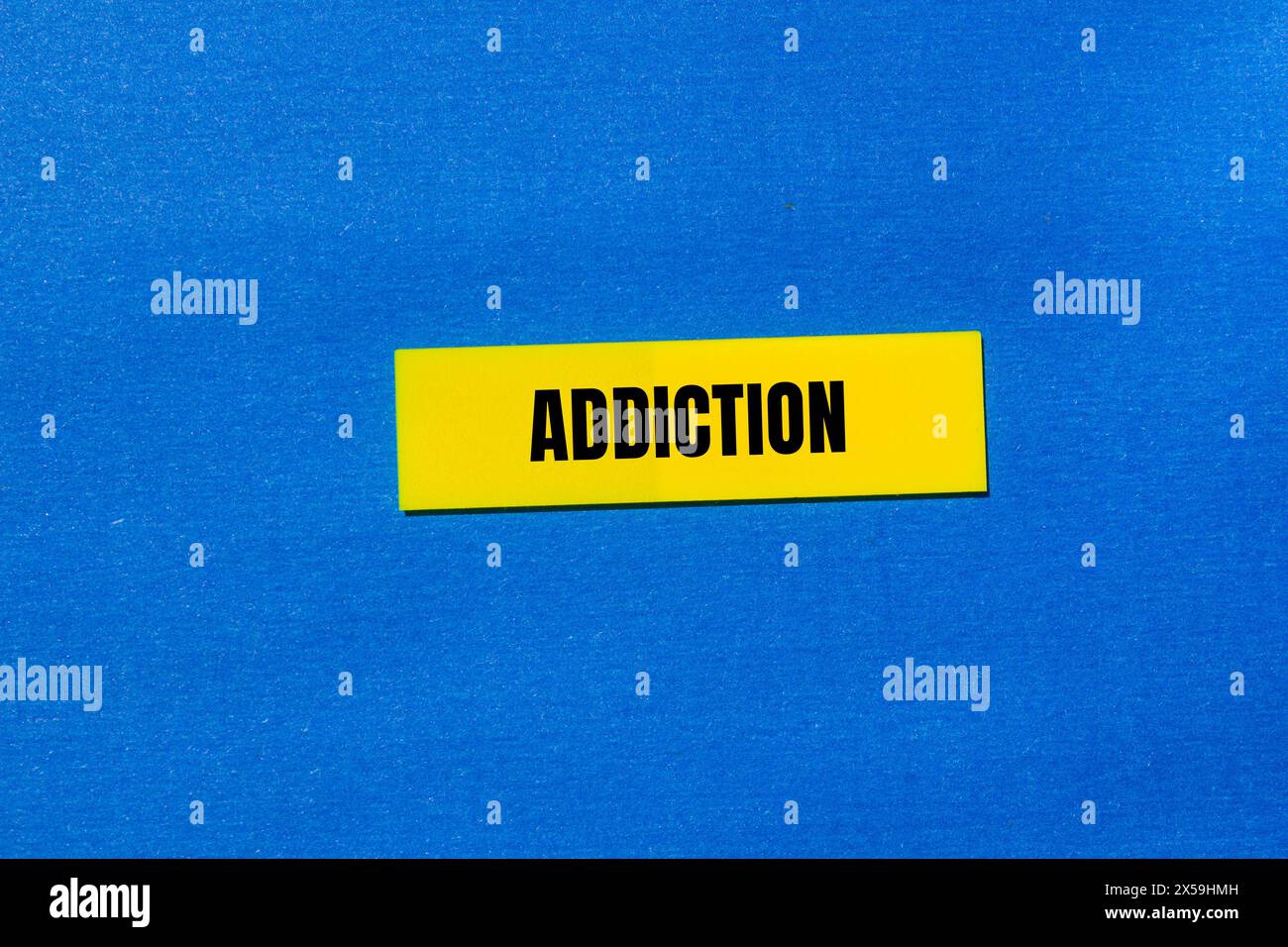 Addiction word written on yellow paper sticker with blue background ...