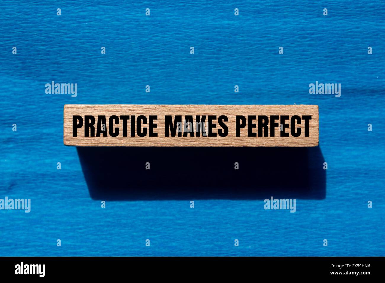 Practice makes perfect words written on wooden block with blue ...