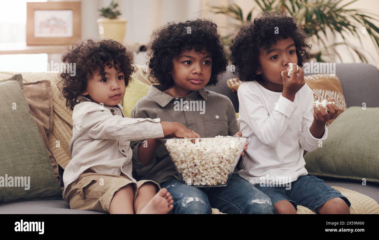 Eating popcorn, couch and children in living room for bonding, cartoons ...