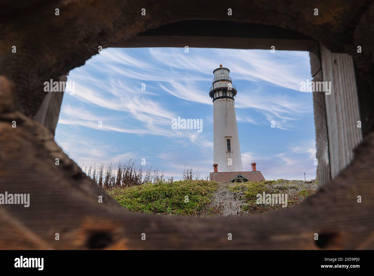 California coastal lighthouse view through square opening, greenery ...