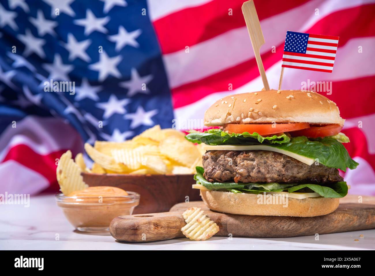 Tasty cheeseburger, chips and sauce with patriotic american flag. July ...