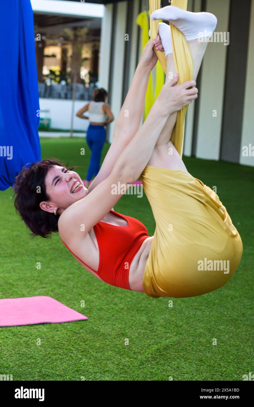 A girl gets tangled in fabric in a funny pose during aerial yoga Stock ...