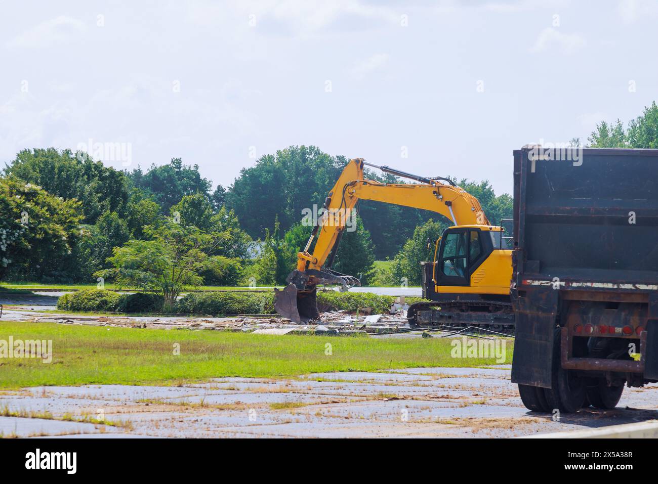 At construction site, an excavator loads concrete waste into dump ...