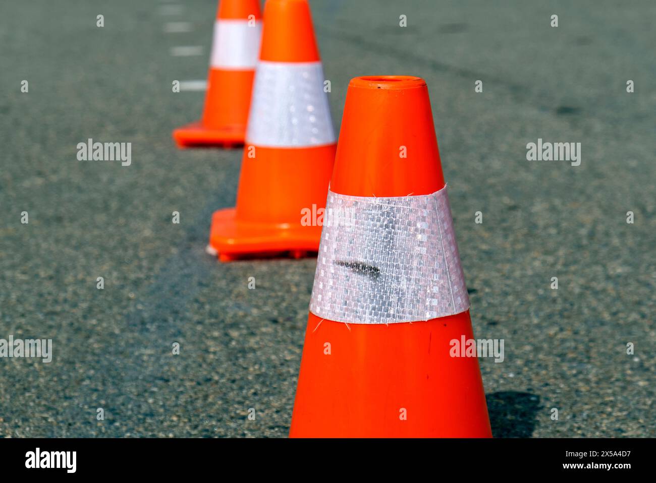 bright orange traffic cones standing in a row on dark asphalt Stock ...