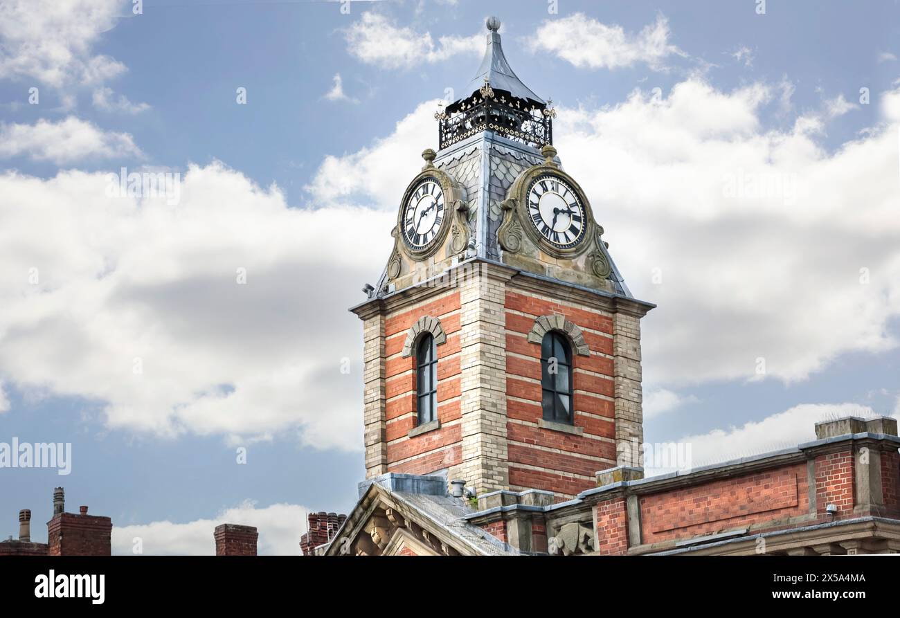 Impressive ornate clock tower made of red brick against a blue cloudy ...