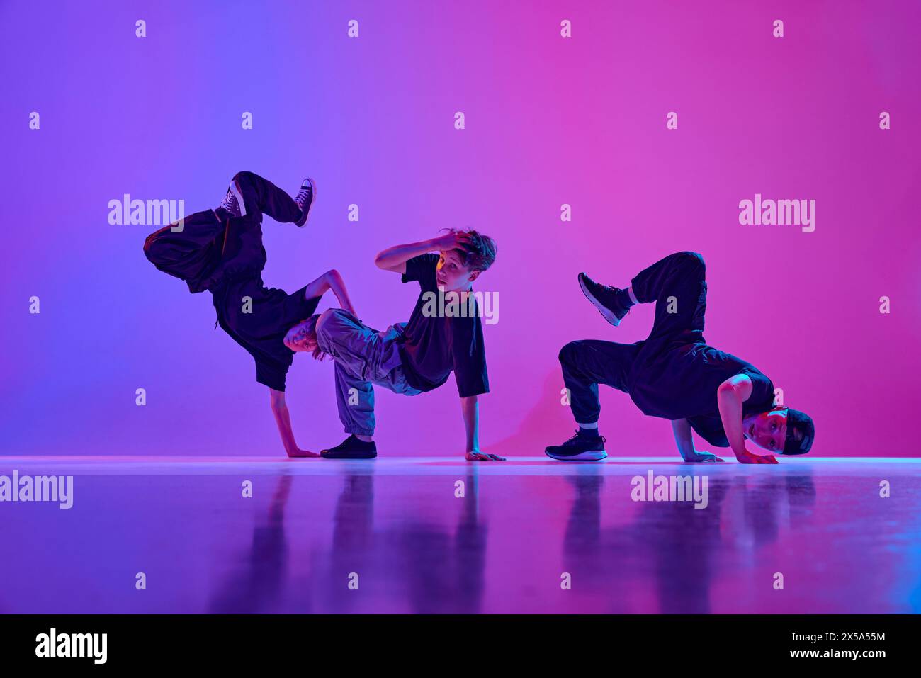 Group of teenagers, boys in casual attire dancing breakdance in mixed ...
