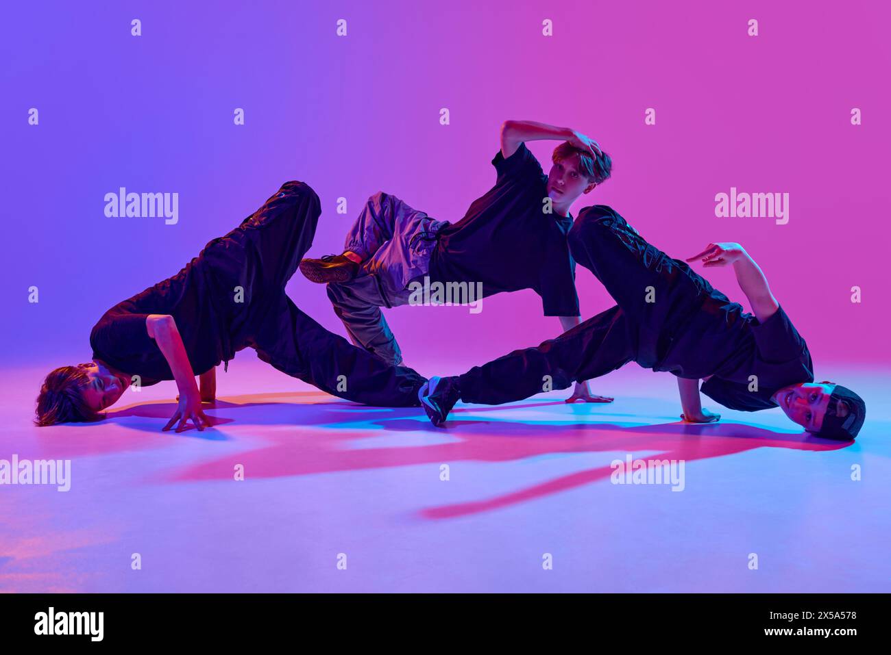 Group of teenagers, boys in casual attire dancing in freestyle in mixed ...