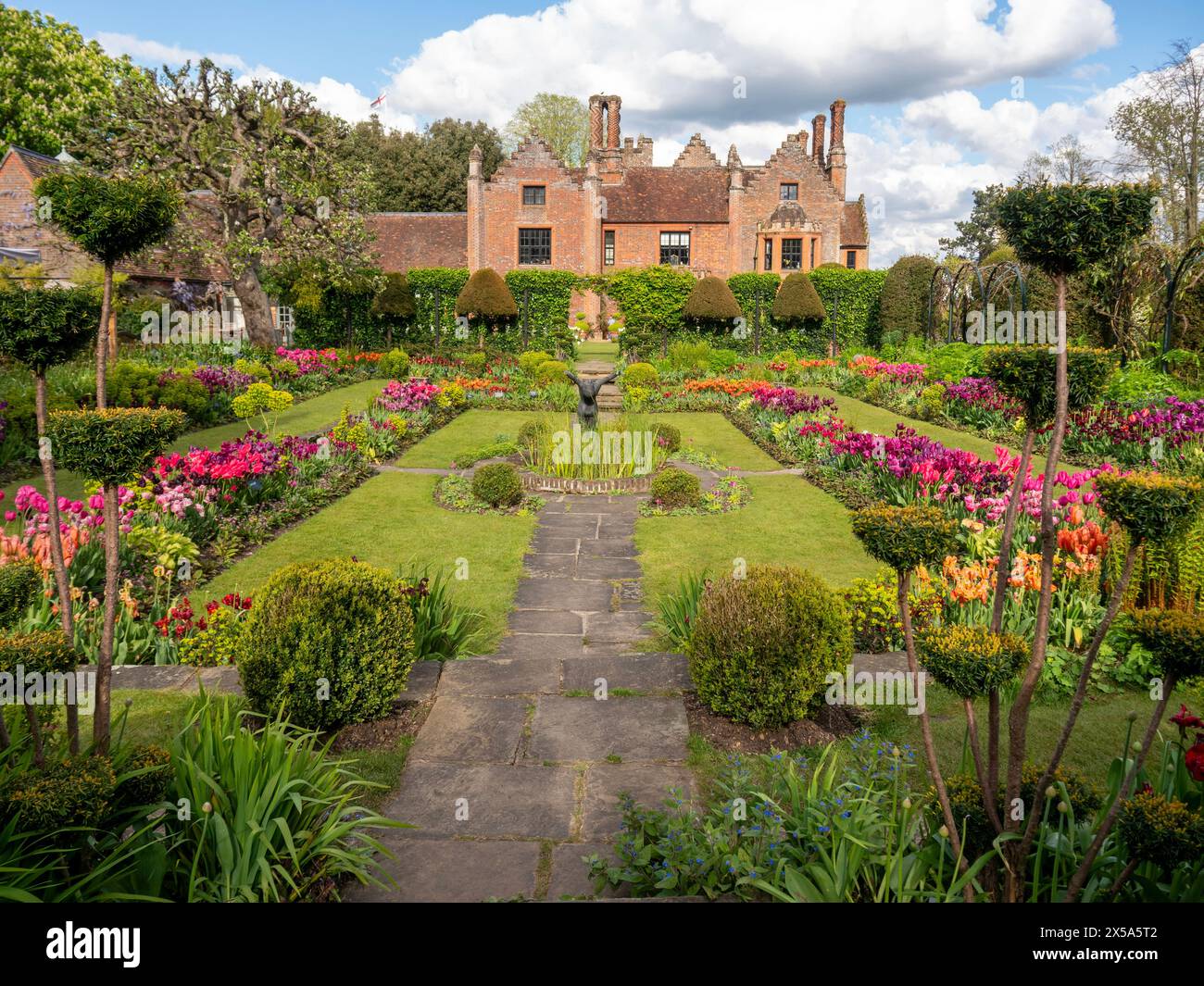 Chenies Manor House and gardens at the height of tulip season. Blue sky ...