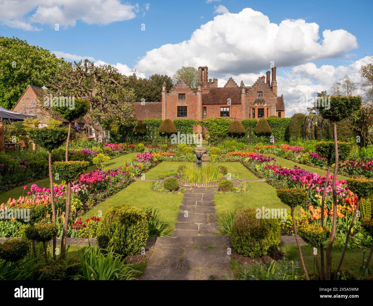 Chenies Manor House and gardens at the height of tulip season. Blue sky ...