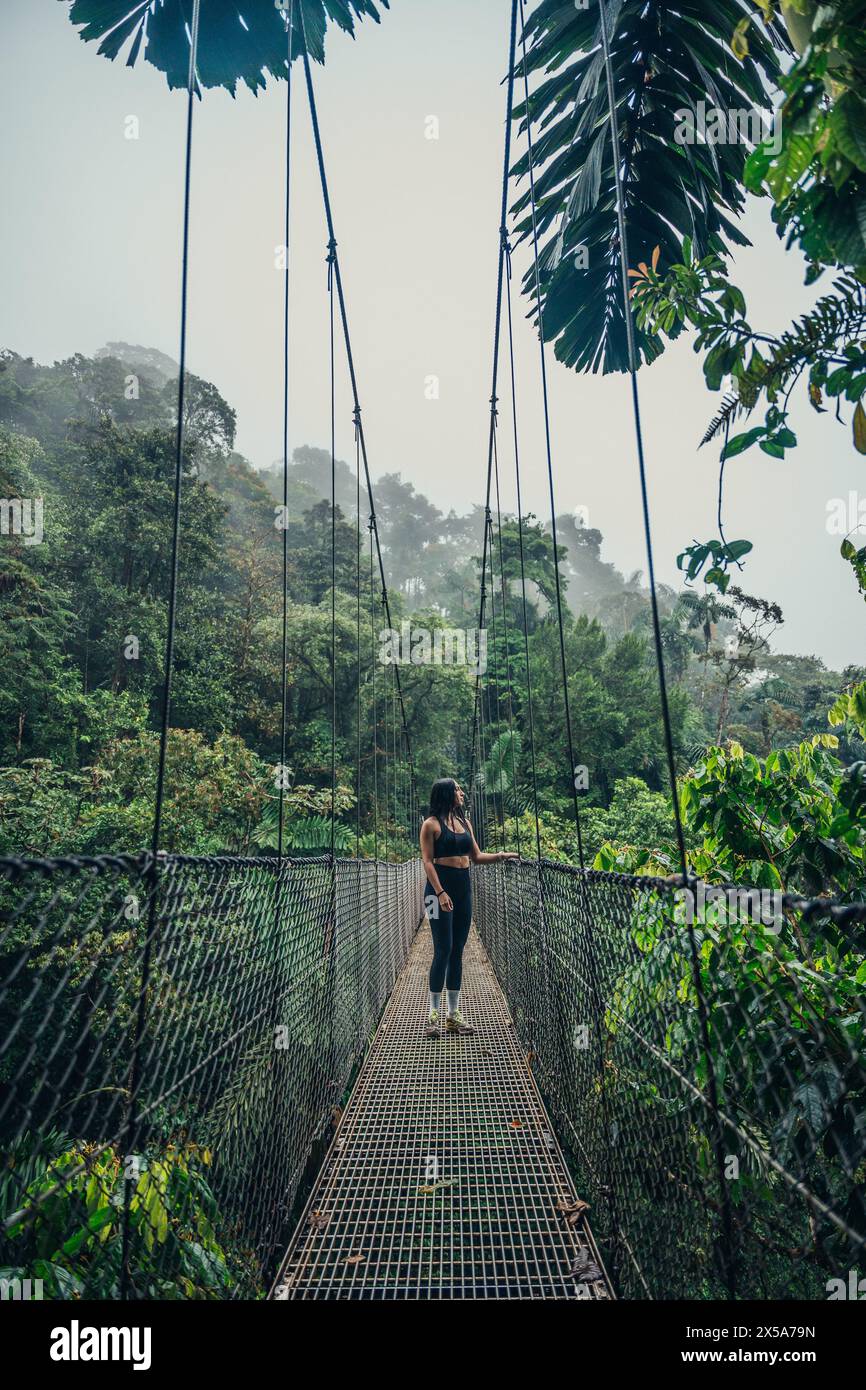 A solo traveler crossing a hanging bridge surrounded by the lush Costa ...
