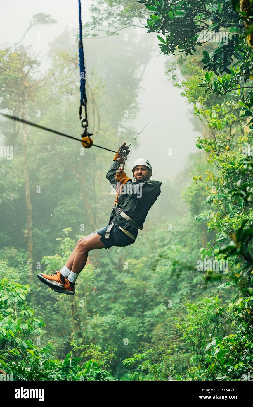 An exhilarated person soars through the foggy air on a zip line amidst ...