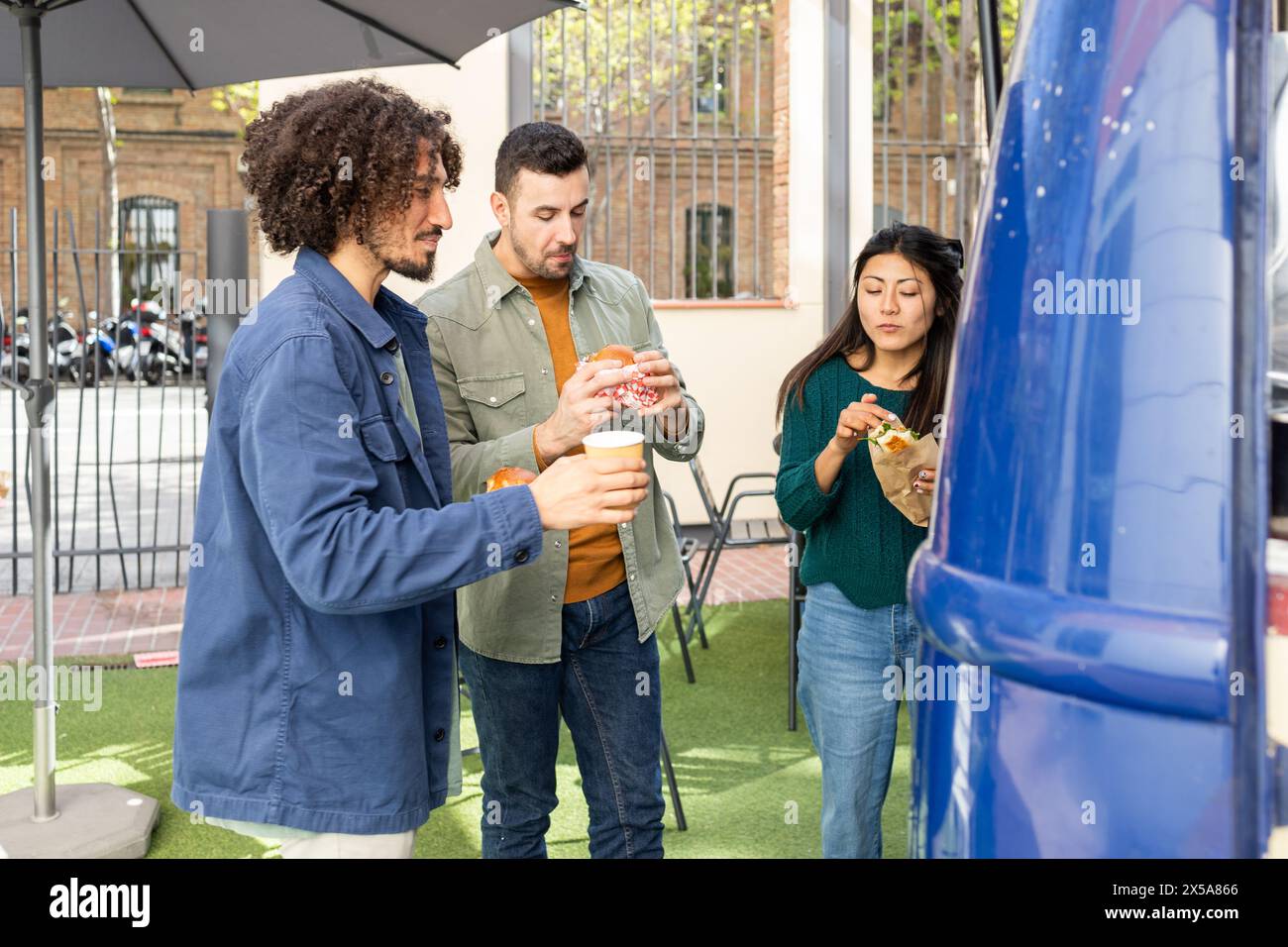 Three friends enjoy a casual meal together outside a vibrant food truck ...