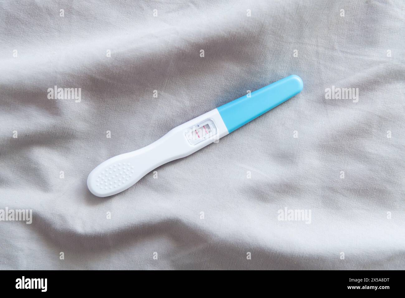 A single pregnancy test with a positive result displayed sits on a ...