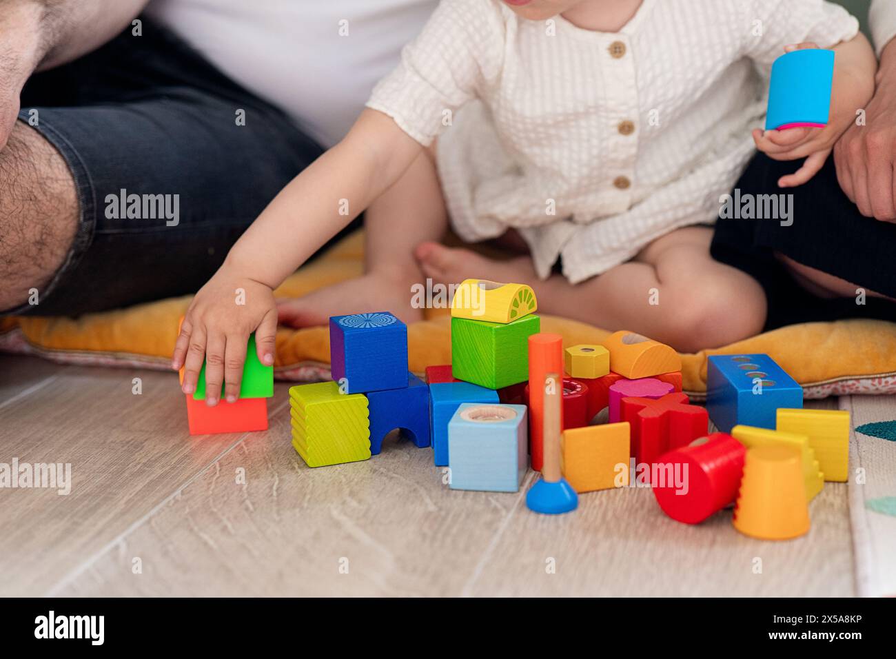 A toddler reaches out to colorful building blocks on the floor ...