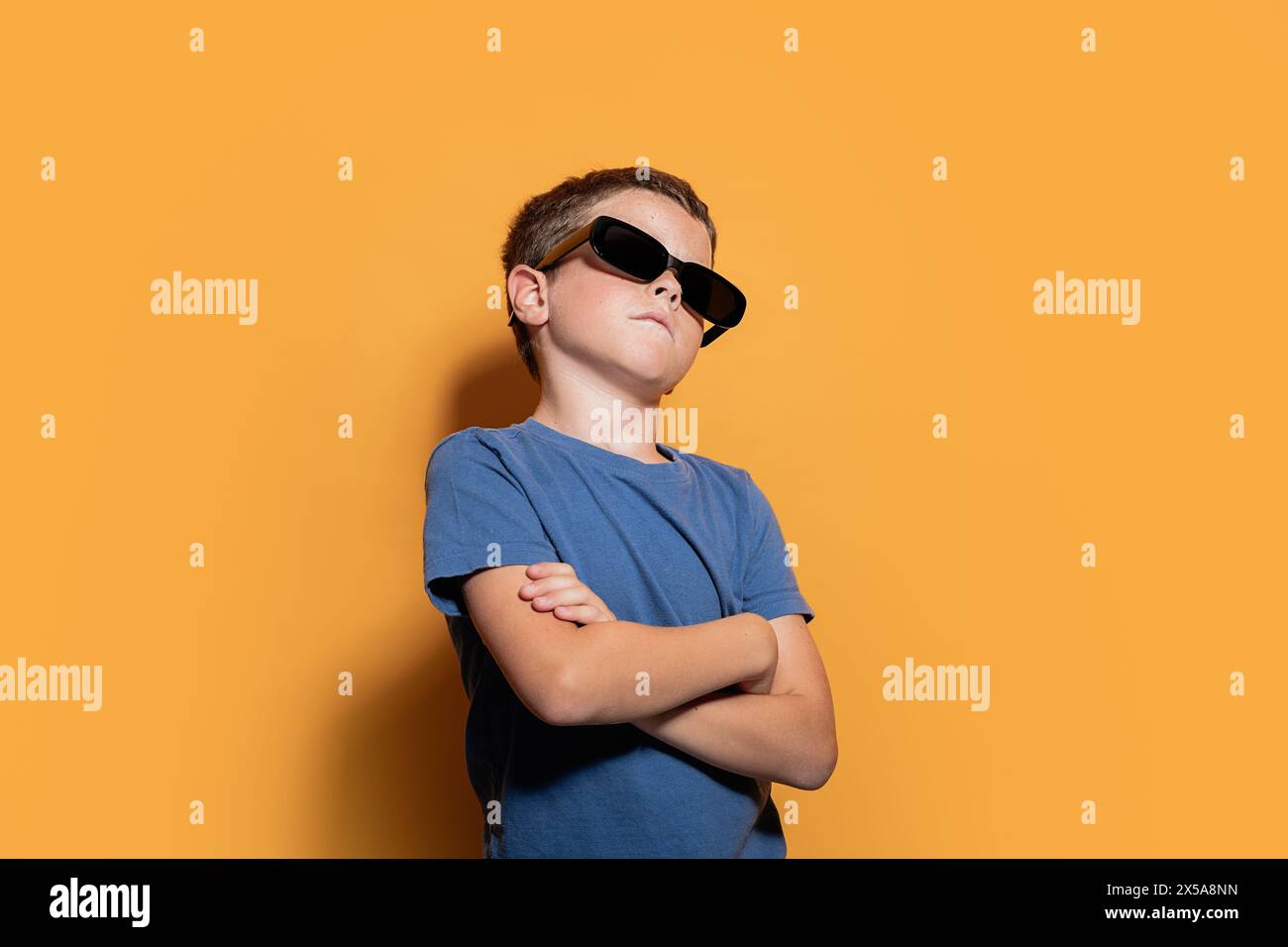 A child with a bold attitude, wearing cool sunglasses, poses with ...