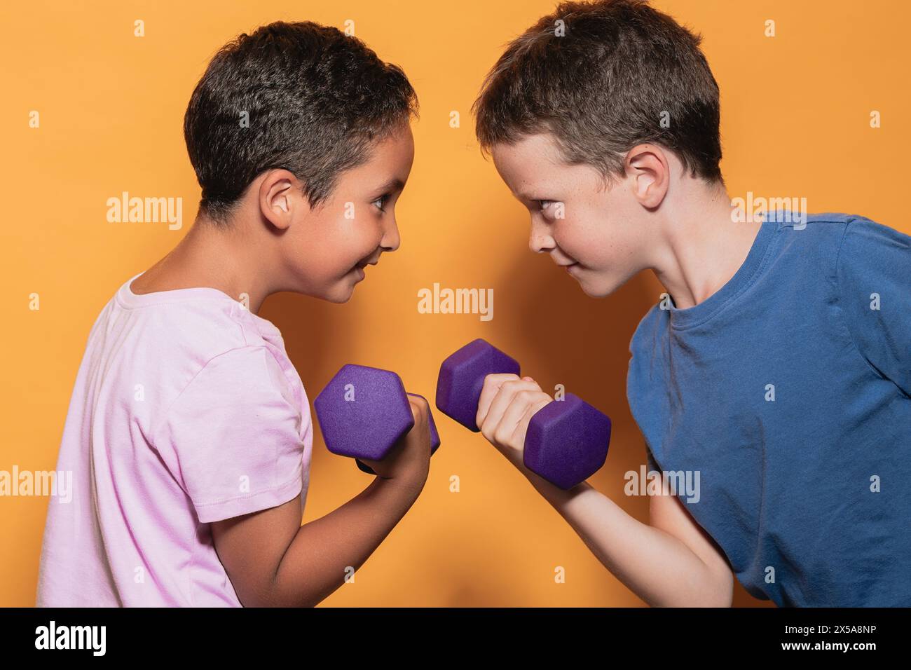 Two young boys face off in a light-hearted arm strength contest, each ...