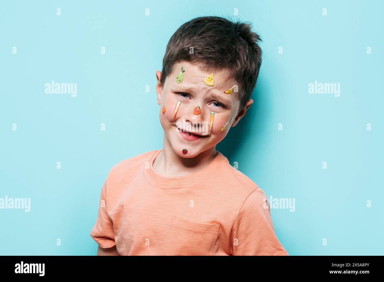 Young boy with a joyful smile adorned with colorful fruit stickers on ...