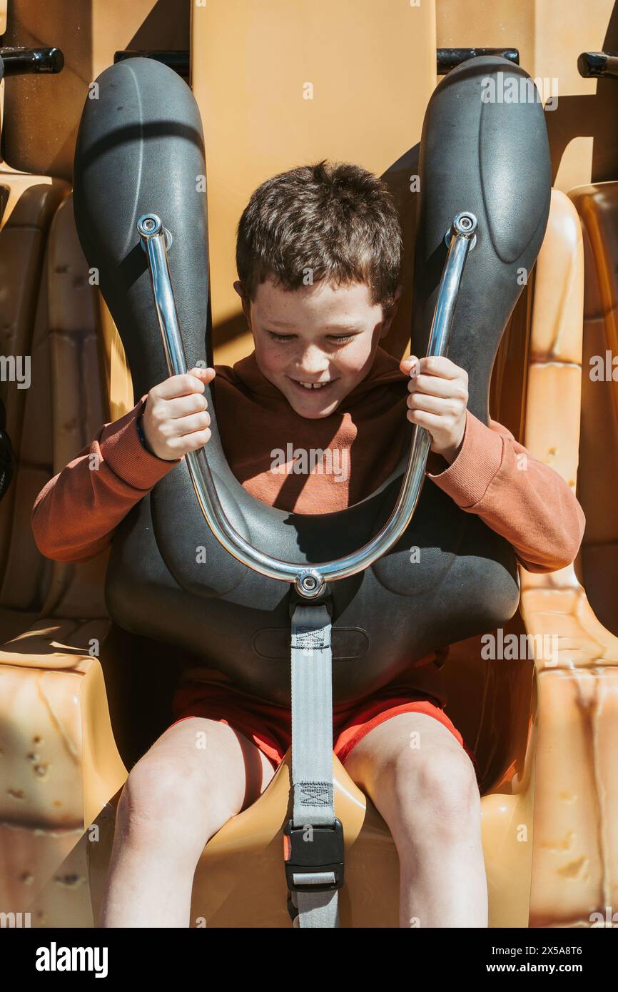 A joyful boy experiences the thrill of a summer amusement park ride ...